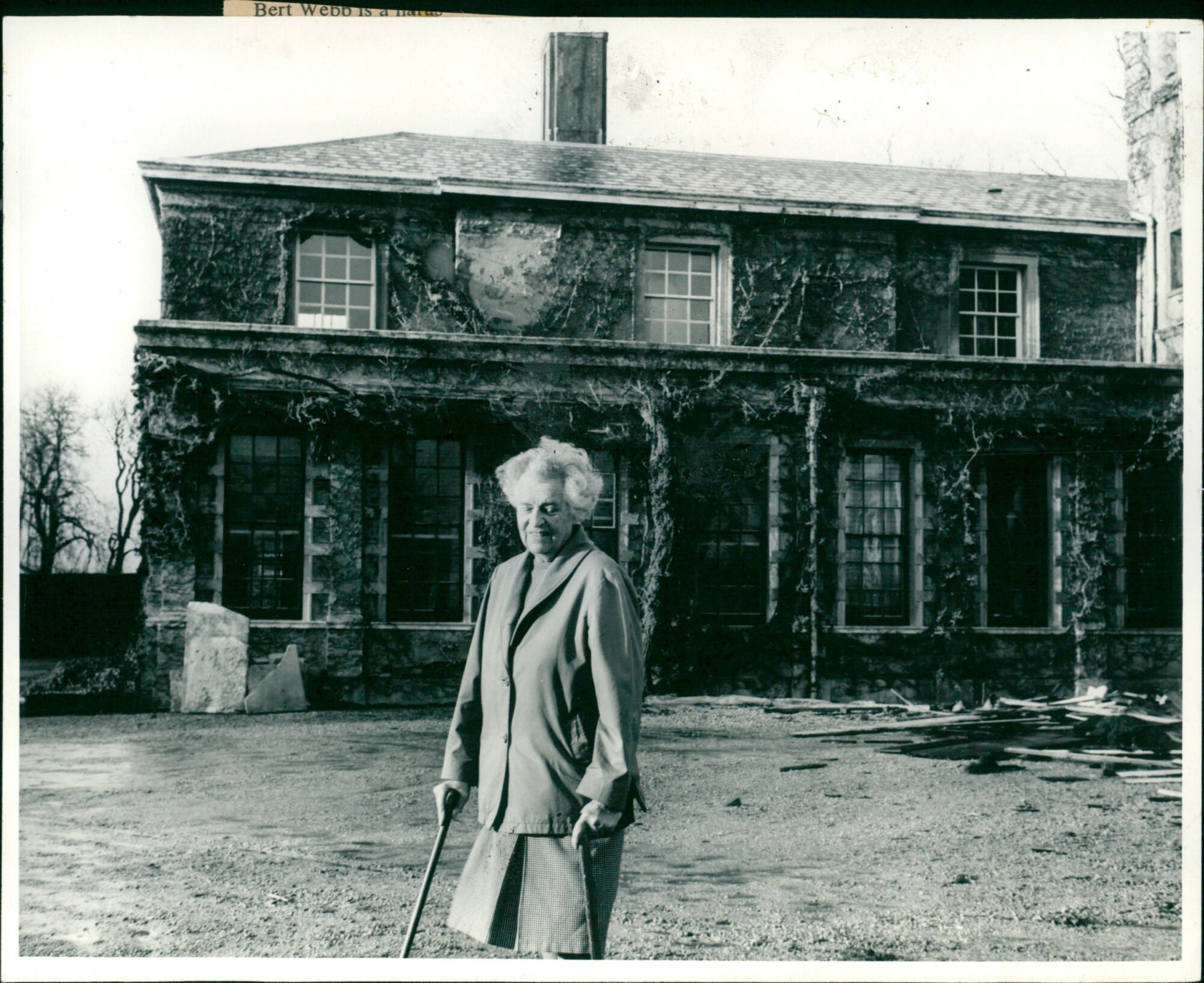 The Hon. Mrs Ruth Wyndham standing outside of a library wing that surv