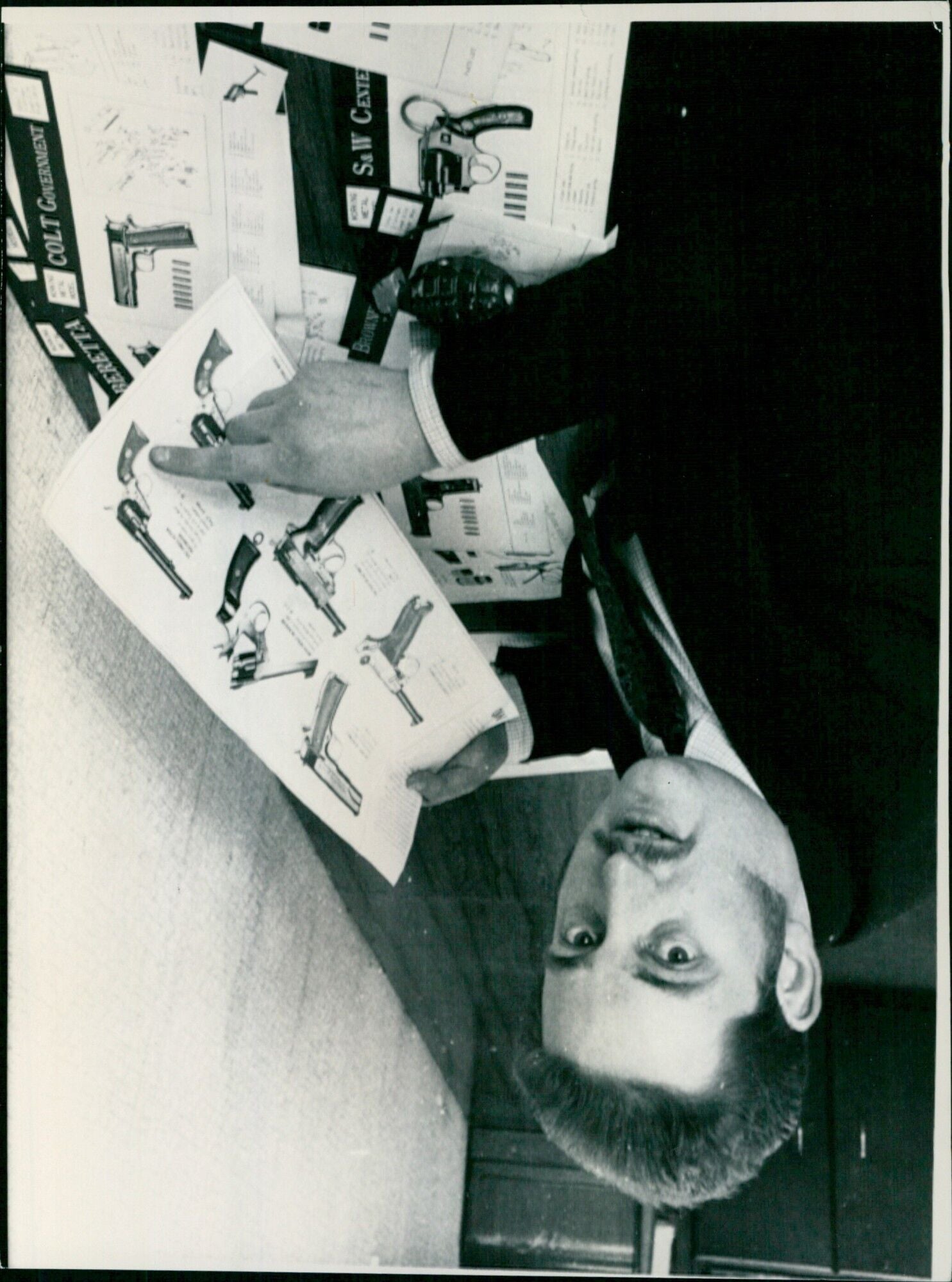 A Colt Government Model 1911 handgun is pictured with several other pi