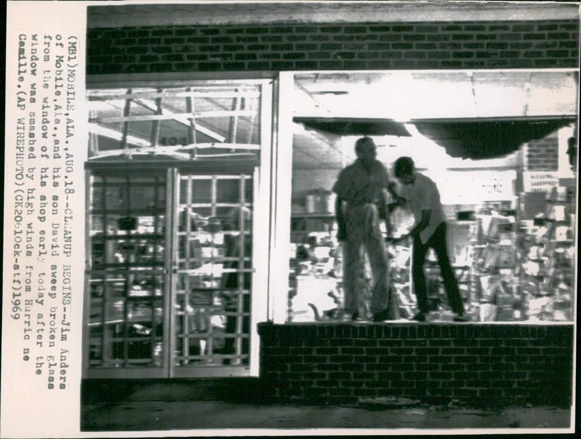 Jim Anders and his son David sweep broken glass from the window of the