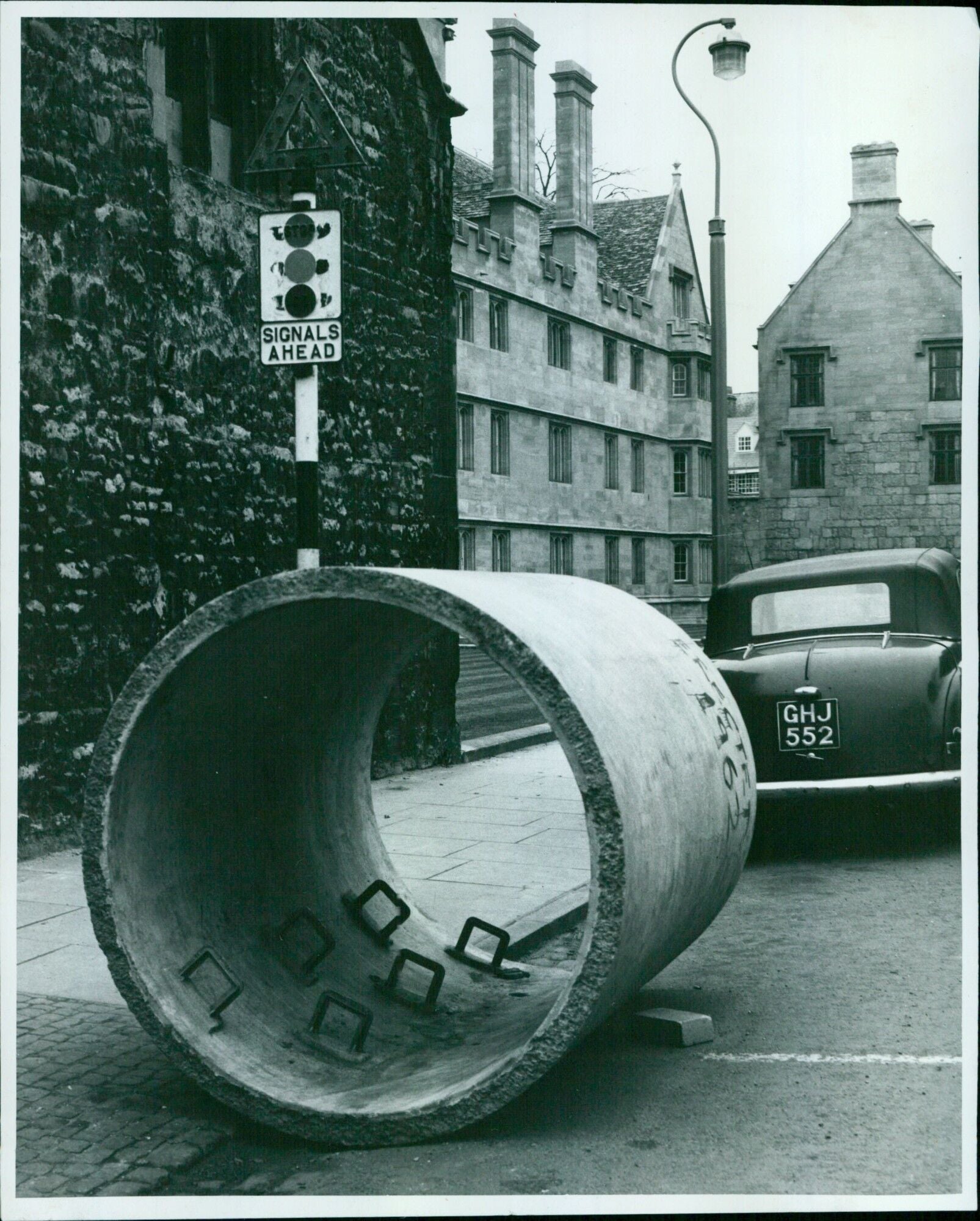 A man holds up a sign reading "Signals Ahead 95 GHJ 552 -4" in front o