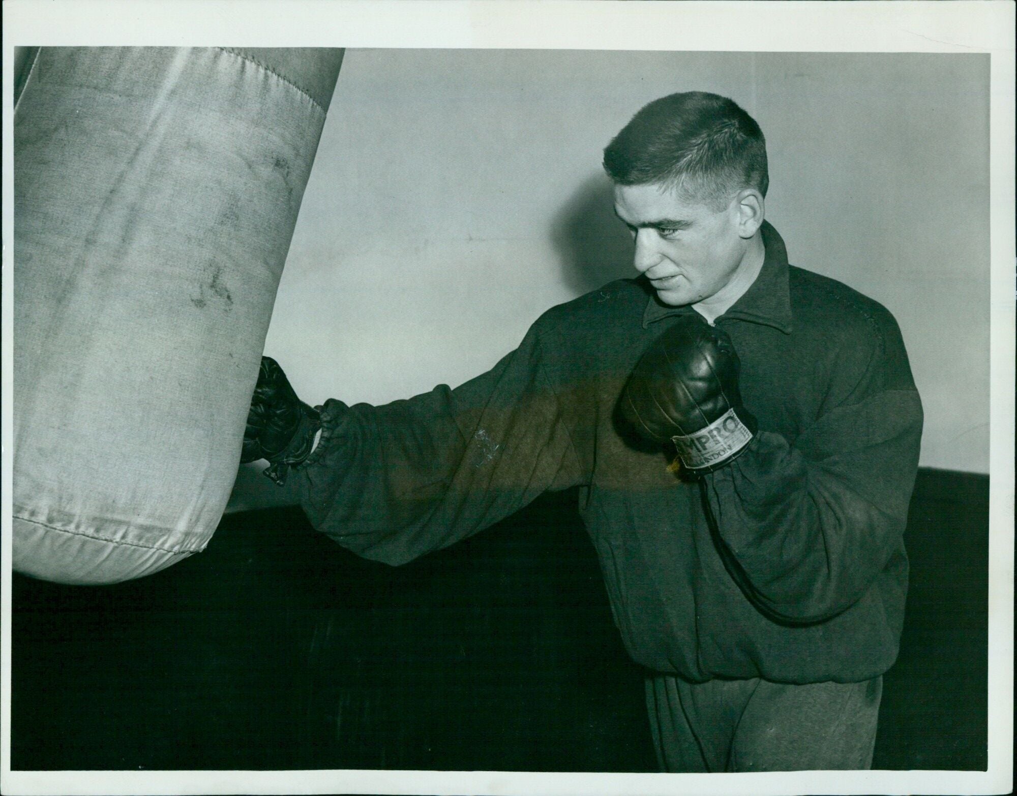 Professional boxer Ronnie Voigt trains on a punchbag. - Vintage Photog